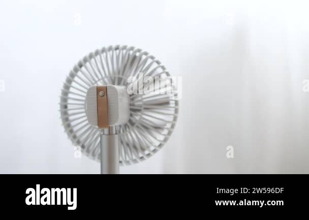 Stylish white electric cooling fan works on a summer day in a home room ...