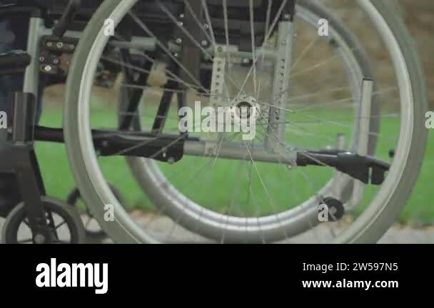 Side view close-up of wheelchair wheel rolling outdoors. Unrecognizable ...