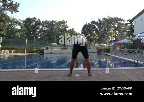 Swimmer stretching his body by the side of the swimming pool. Slow ...