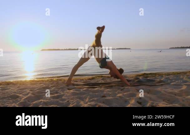 barre workout. stretching outdoors. yoga beach. Athletic young woman is ...