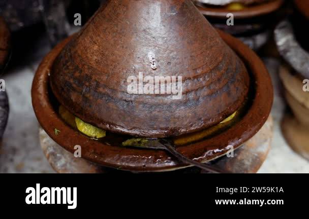 Traditional tagine (tajine) meal cooking in the clay pot outdoors in a ...
