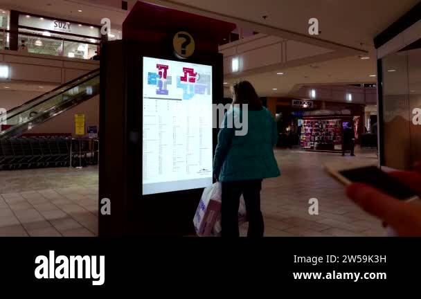 Woman checking store position in front of directory sign inside ...