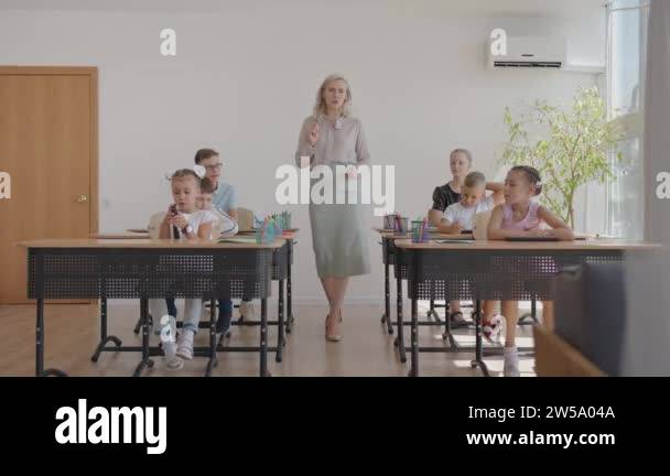 Female teacher controlling learning process in primary school. A female ...