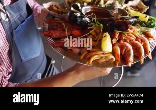 Waiters carries mixed seafood set, lobster shrimp, king prawns, mussels ...