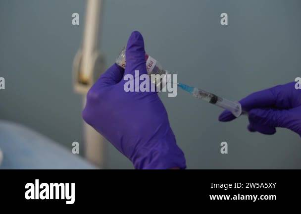 Doctor dials drug into syringe through needle. Doctor is preparing for ...