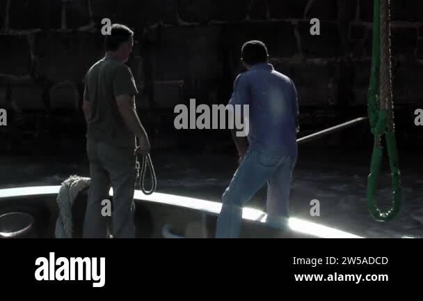Crew of a Tugboat catching Mooring Ropes of a Cargo Ship in the Port of ...