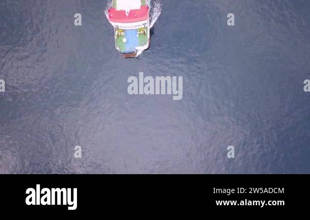 Aerial tilt up shot of passengers in ferry boat sailing on blue sea ...