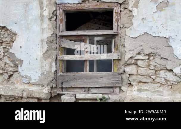 Window without glass, boarded up by boards in an old decaying house ...