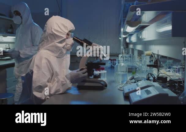 Slowmo PAN of female epidemiologist in disposable coveralls, goggles ...