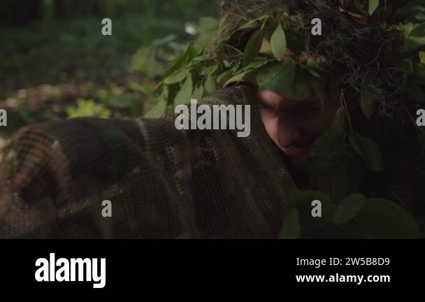 Sniper looking through scope of optical sight, taking aim in forest ...