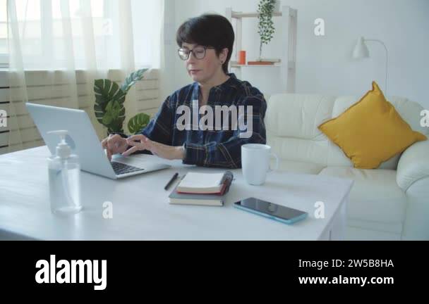 Remote work concept. Mature woman in pajamas working at home with ...