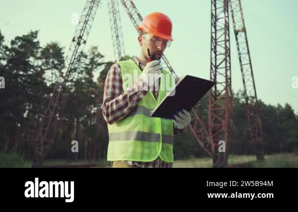 Electrical engineer wearing hard hat and safety vest checking ...