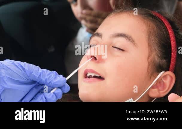 Pediatrician taking nasal mucus test sample from elementary age girls ...