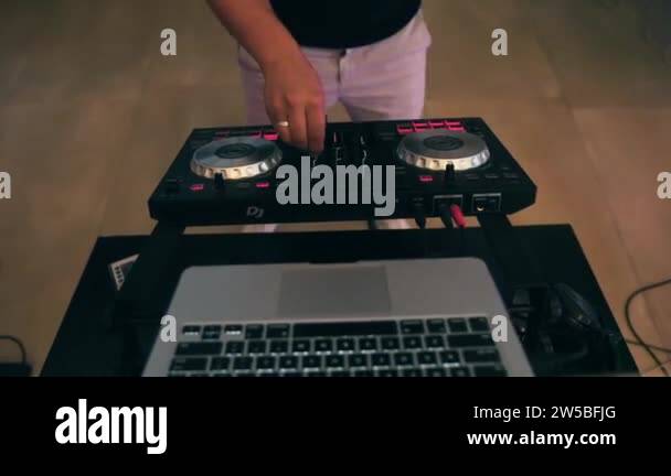 Caucasian DJ with wedding ring on hand stands behind laptop and music ...