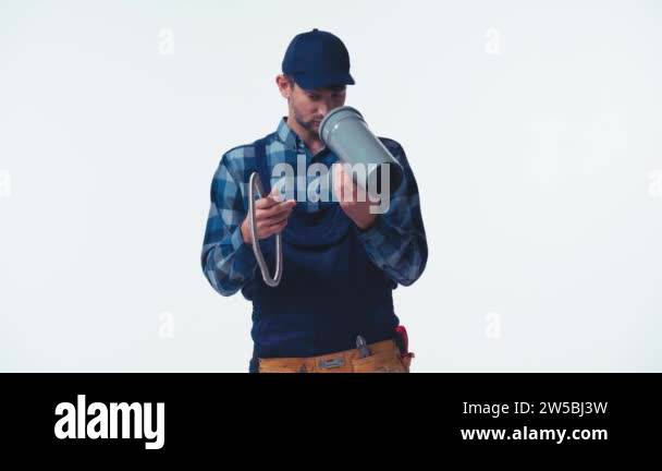confused plumber in uniform holding hose and tube isolated on white ...