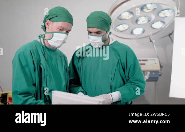Surgeon men doctor checking monitor and analyse the report, while staff ...