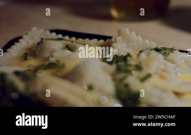 Close-up of hot cooked ravioli covered with melted butter and chopped ...