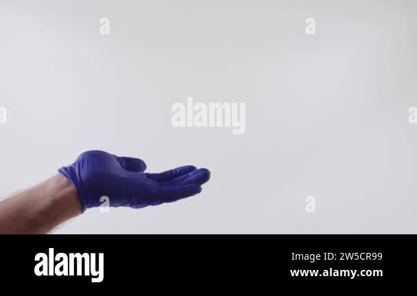 A hand in medical gloves is holding something on a white background ...