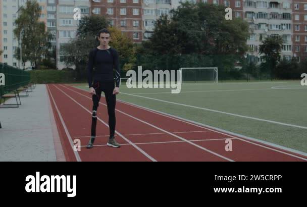 Young disabled man with prosthetic running blades standing at sports ...
