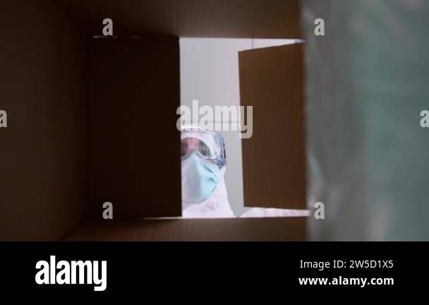 A health worker is opening a box with masks and medical supplies. He is ...