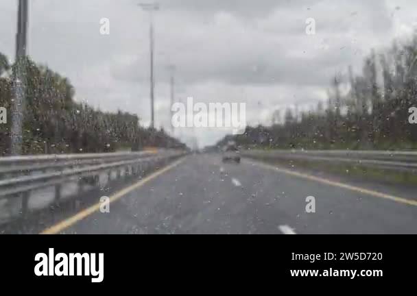 original time-lapse video of road view through windshield car window with going raindrops during ...