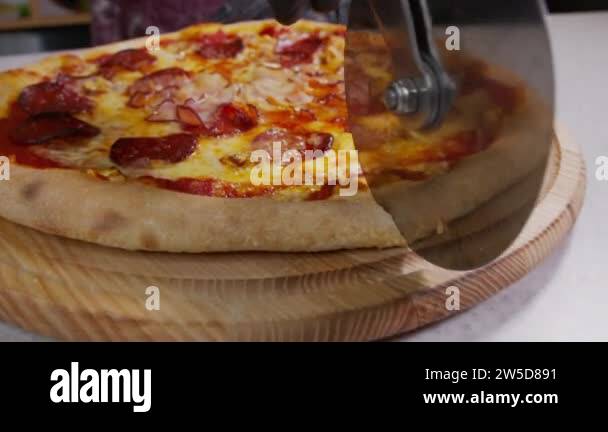 Cutting pizza with a round cutter knife. Close-up of delicious pizza ...