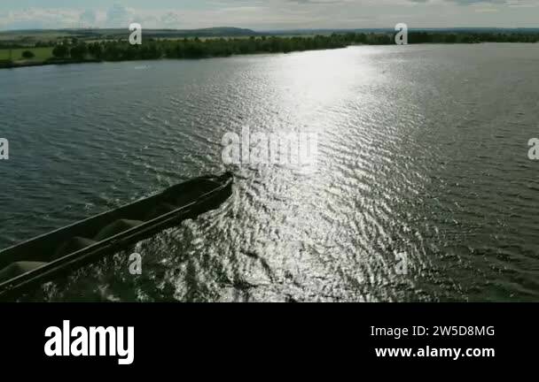 A dump scow transports sand down the river. A bird flies by. Collecting ...