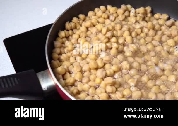 Cooking chickpeas in hot water. Dry garbanzo beans submerged in water ...