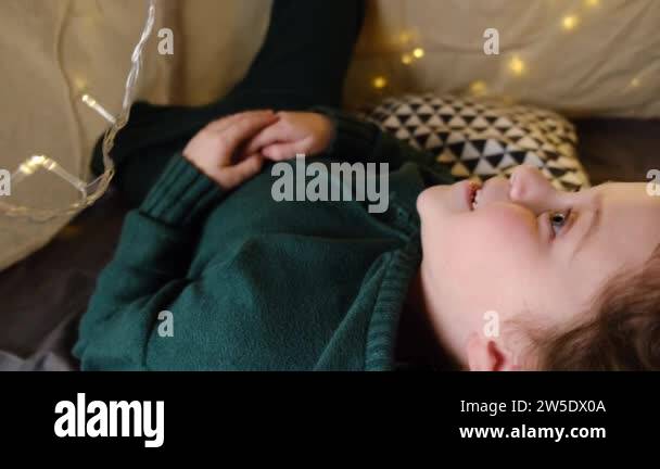 Close up side view of cute positive little preschool girl lying in tent ...