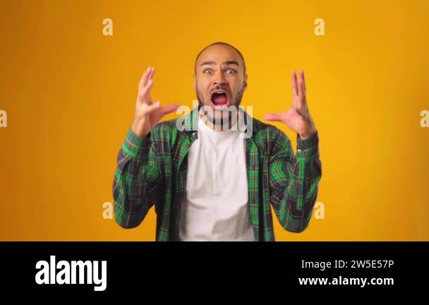 Very scared shocked man screaming and putting hands up against yellow ...