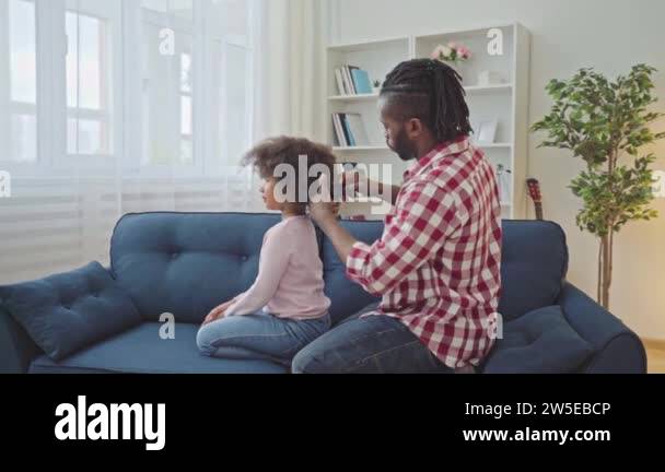Young black father combing natural afro hair of daughter, making ...