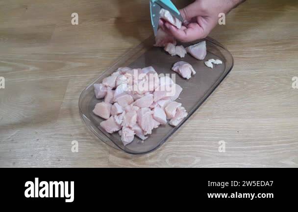 Chicken meat is cut into pieces in kitchen with sharp food scissor ...
