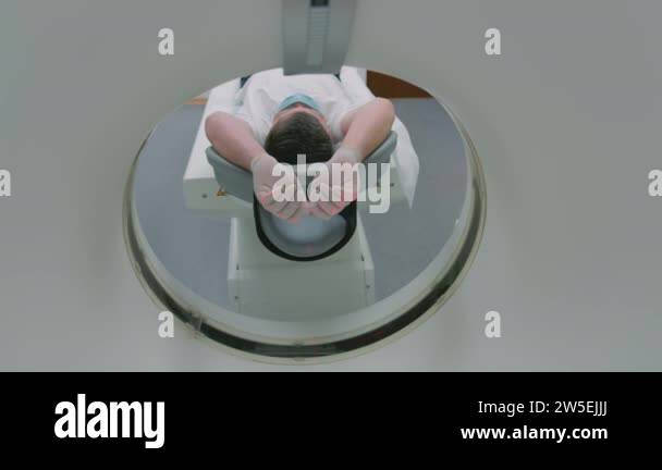 A patient in a protective medical mask lies in a modern computed ...