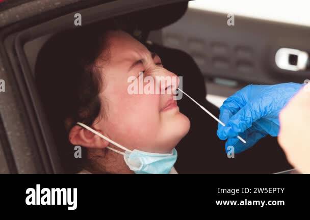 Pediatrician taking nasal mucus test sample from elementary age girls ...
