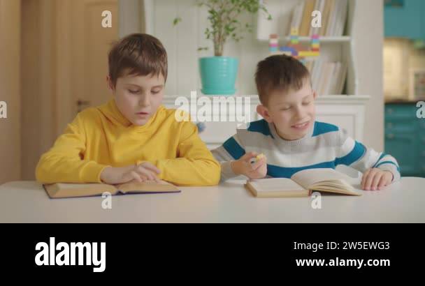 Two kids with autism reading paper books while studying at home during ...