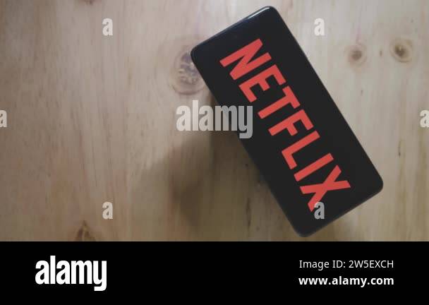 Netflix logo on a Smartphone. Desk with Netflix logo and a hot cup of ...