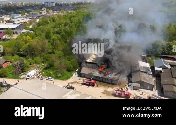 Aerial view of firefighters extinguishing ruined building on fire with ...