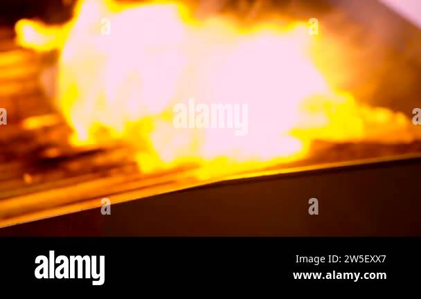 Beef steaks on grill with blazing flame close up view. Chef hands turn ...