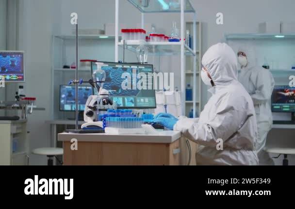 Chemist in ppe suit typing on computer checking virus development Stock ...