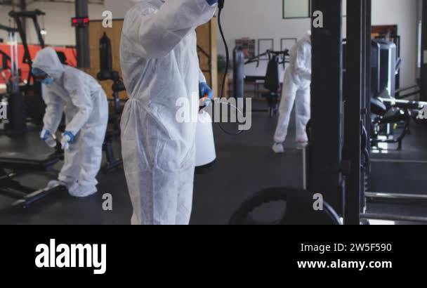 Team of health workers wearing protective clothes cleaning gym by using ...