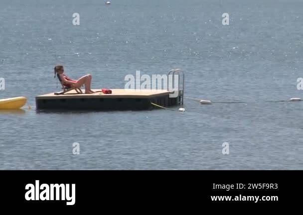 Woman sunbathing on a raft with a rubber dinghy tied to it (2 of 2 ...