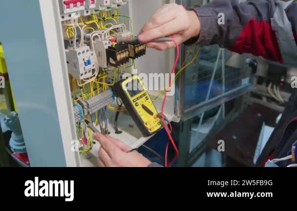 Electricians hands testing current electric in control panel ...