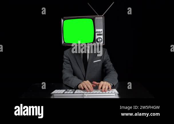 Man typing with TV on head showing green screen on the screen Stock ...