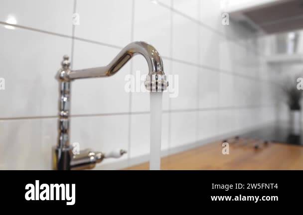 Water flowing out of stainless steel tap. Dish rack holds dishes ...