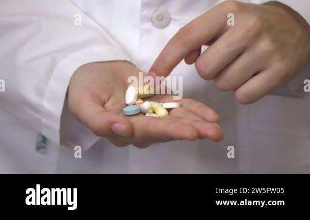 Pain reliever pills in the female hand of a medical professional in a ...