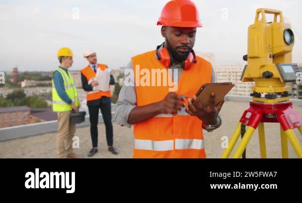 African American man topographer in casque measuring angle with total ...