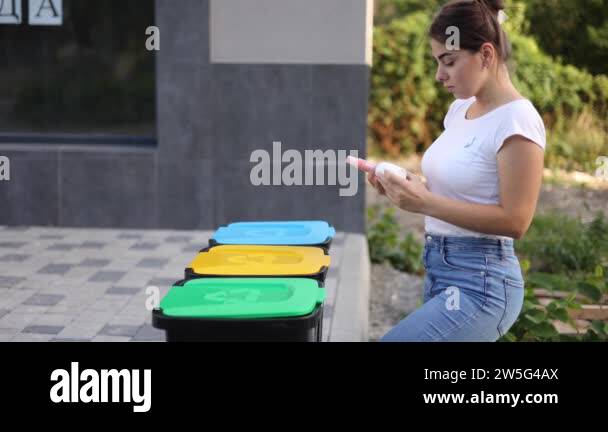 Woman throwing out in recycling bin washed and empty shampoo and ...