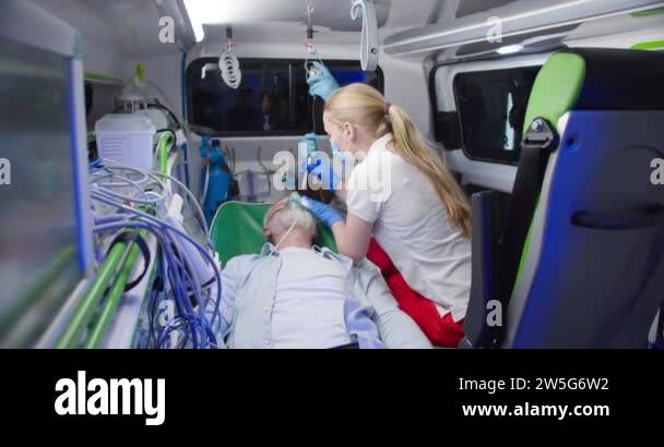 Mixed-races paramedics saving life of old man in ambulance. Medic ...