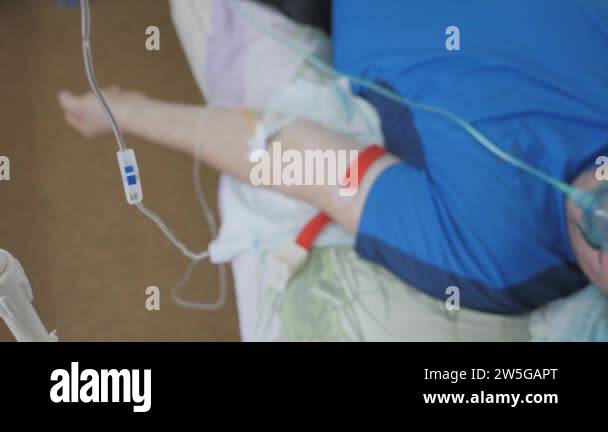 Sick man in a hospital bed. An intravenous drip is installed in the arm ...
