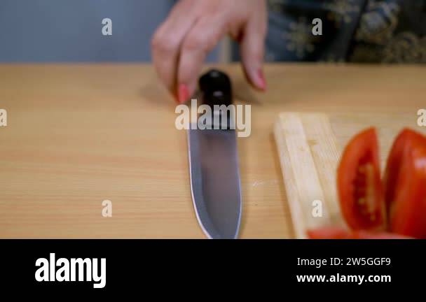 Indian chef using a sharp knife to slice a red and ripe tomato ...